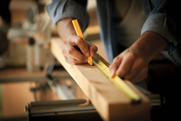 Carpenter Measuring a Wooden Plank - Broder